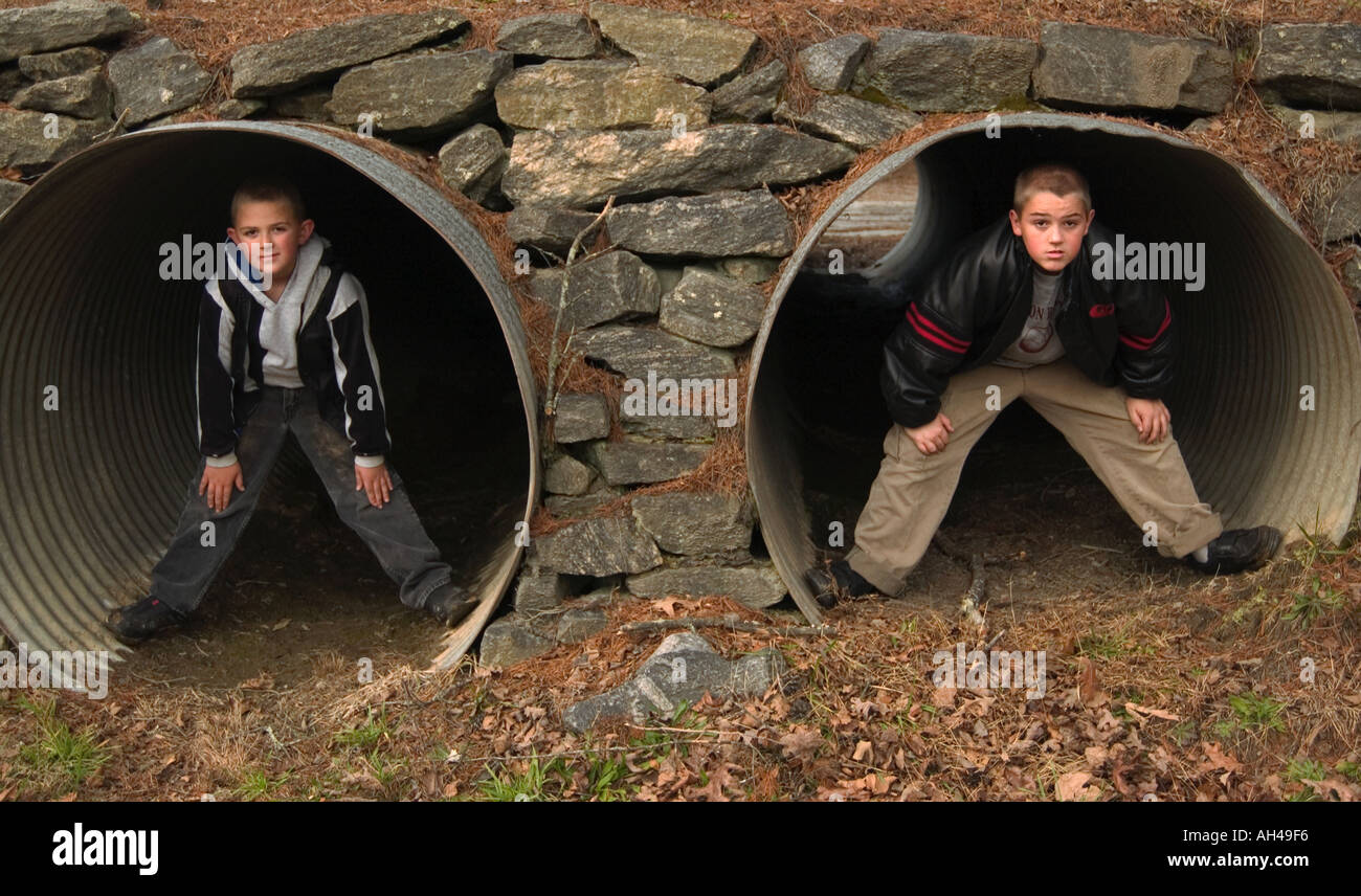 Two young Caucasian boys playing inside a large drainage pipe ...