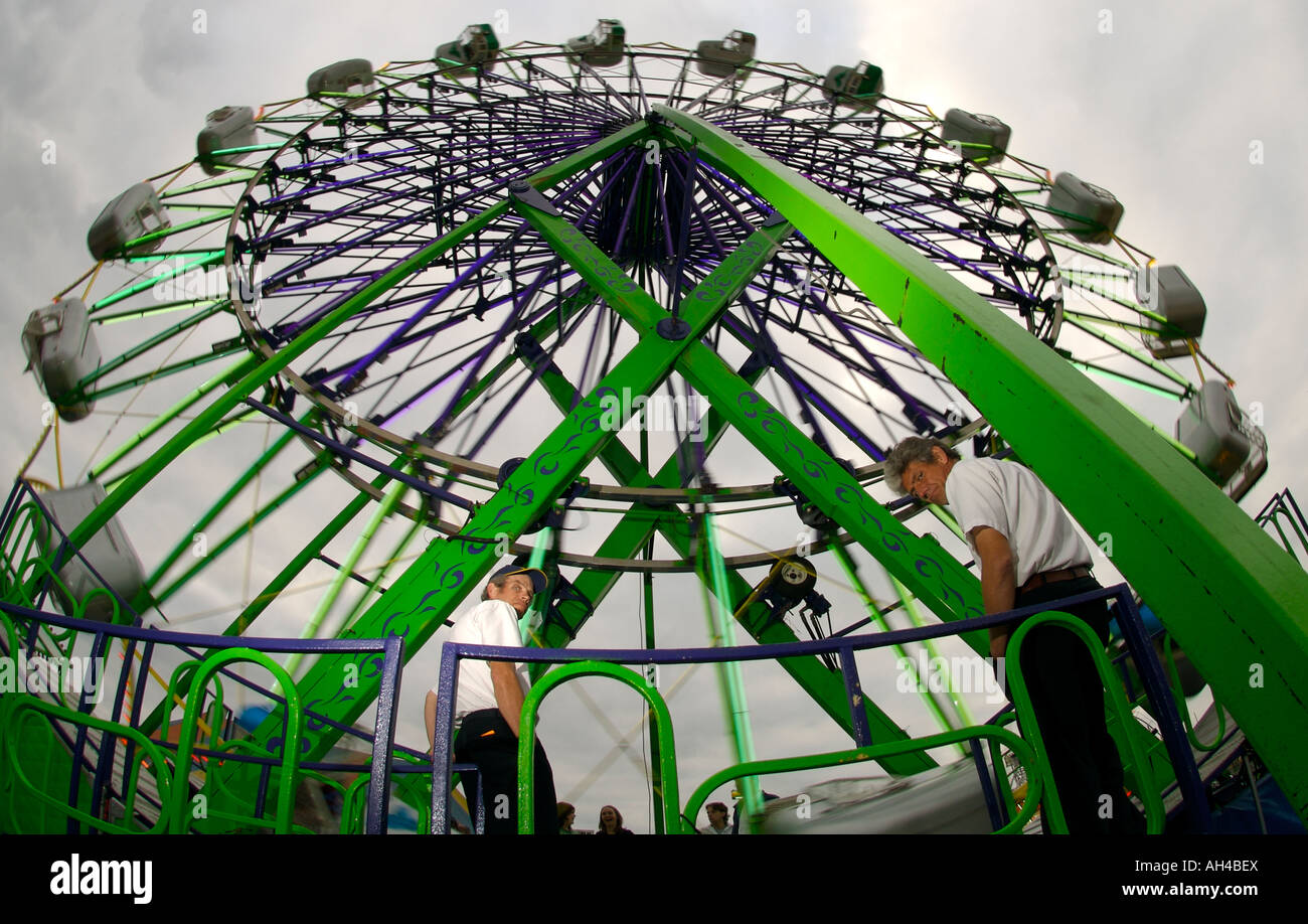 Carnival employees operate the Skydiver ferris wheel on a cloudy day at ...