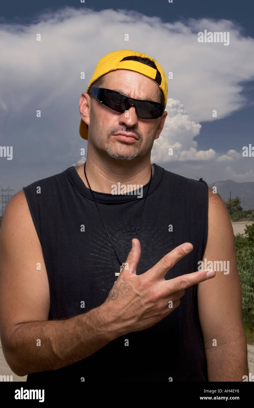 Man outdoors gesturing a gang sign Stock Photo - Alamy