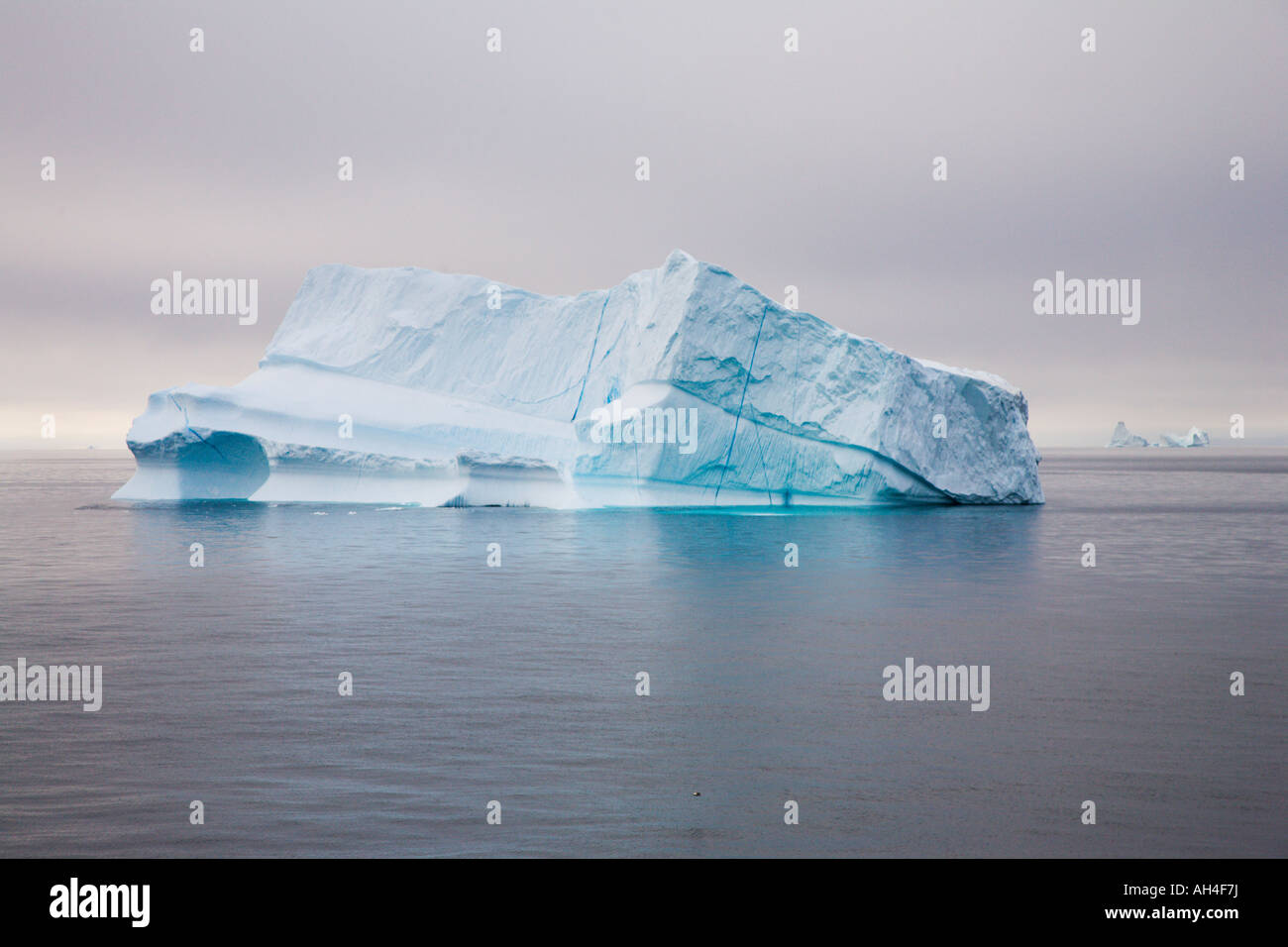 Huge iceberg on a very calm sea under overcast sky in Disko Bay in the ...