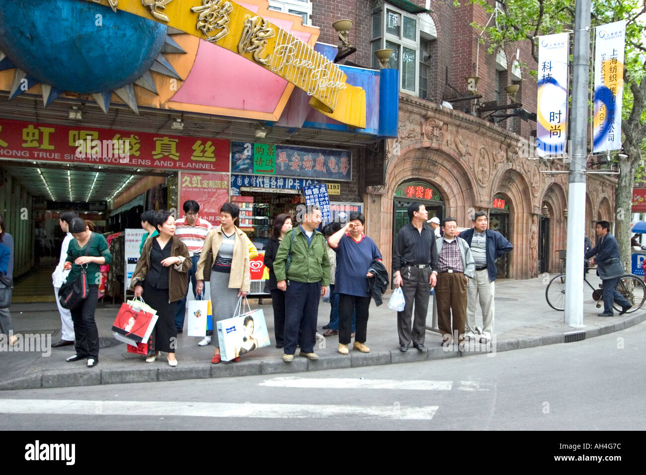 Pedestrians and shoppers wait at a busy intersection in Shanghai China ...