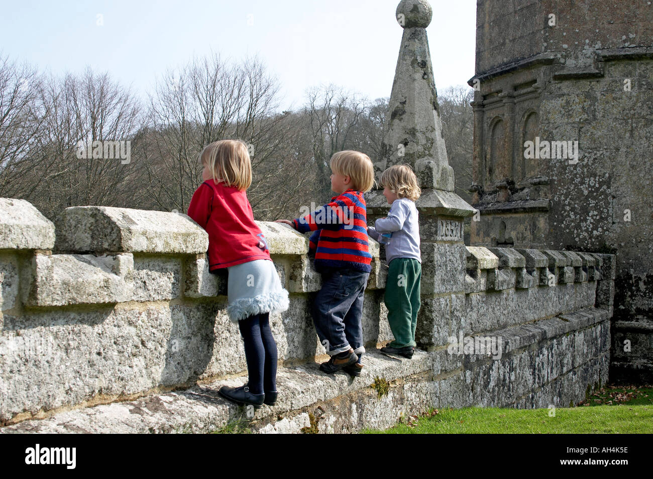 Three children looking over a wall Stock Photo - Alamy