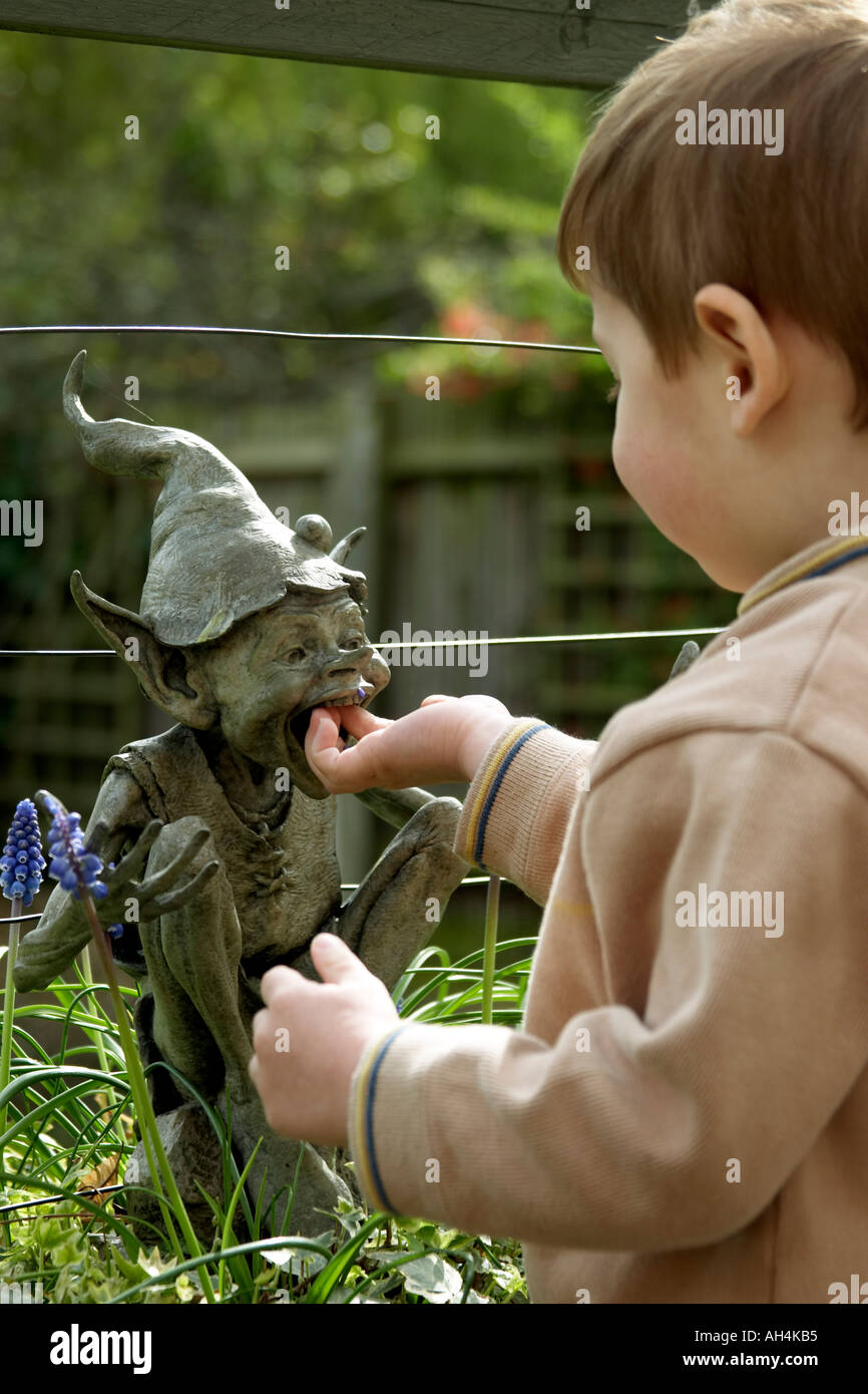 Attractive young boy child in a suburban garden in spring feeding an ...