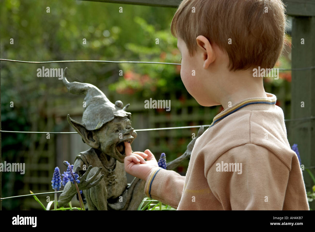 Attractive young boy child in a suburban garden in spring playing with ...