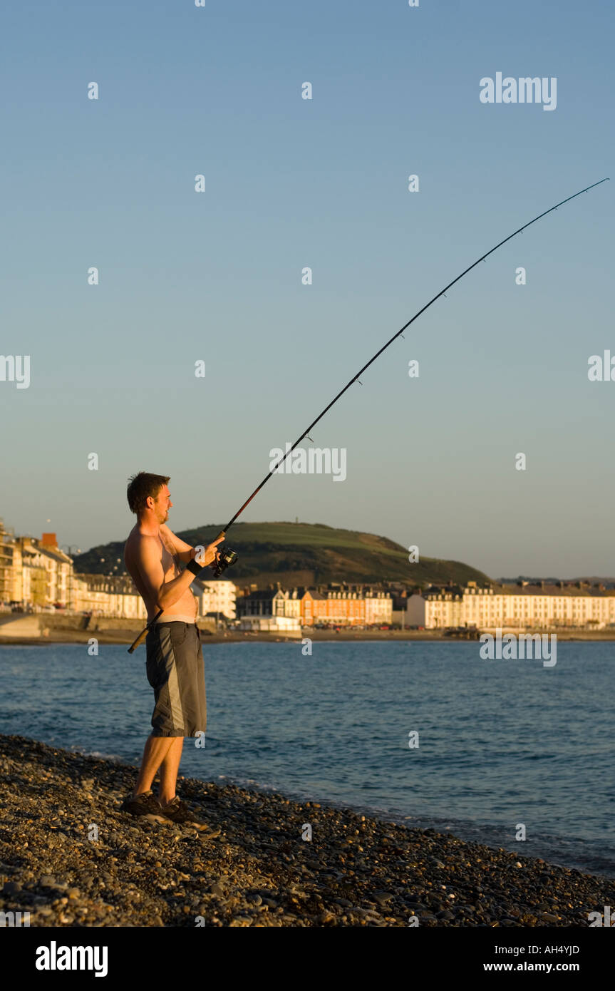 Man with rod and line fishing for mackerel off the beach Aberystwyth ...