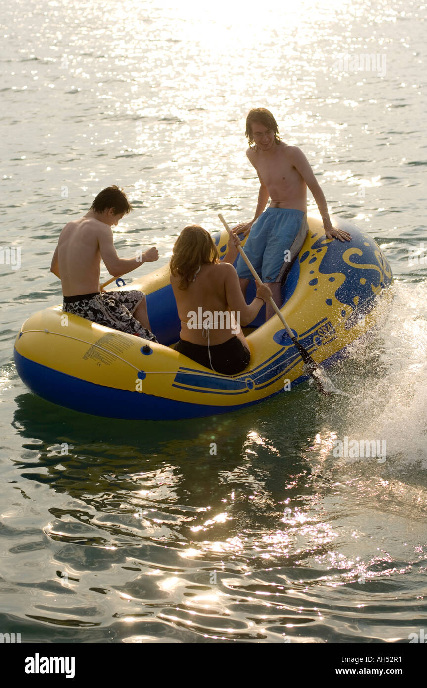 Three young people friends having fun in an inflatable dinghy on the ...