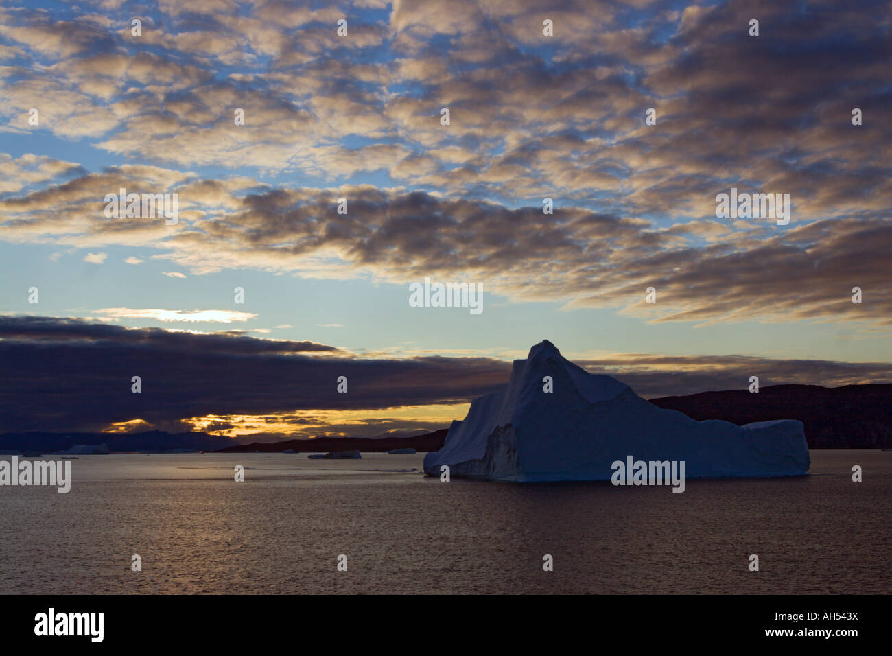 Huge iceberg on a very calm sea with sunset sky in Disko Bay in the ...