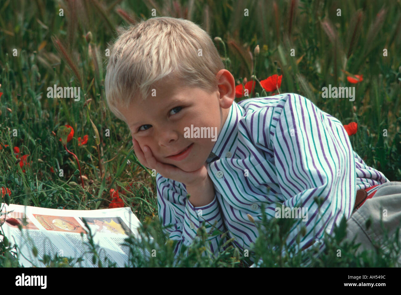 Young boy reading on flowery grass Stock Photo - Alamy