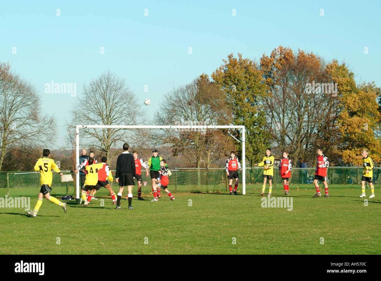 Football match in progress on village green pitch back view of referee ...