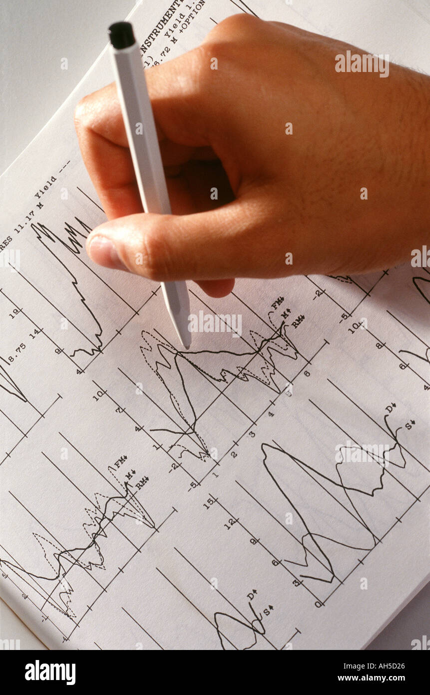 Hand holding pen on graph of financial statistics Stock Photo - Alamy