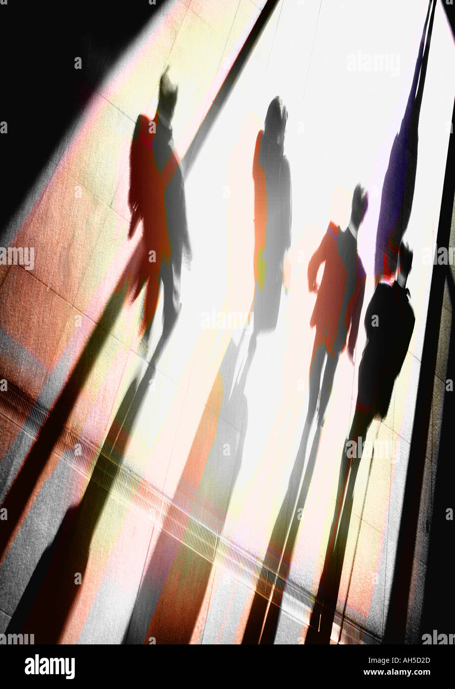 Business people walking through sunlight casting long shadows on ...