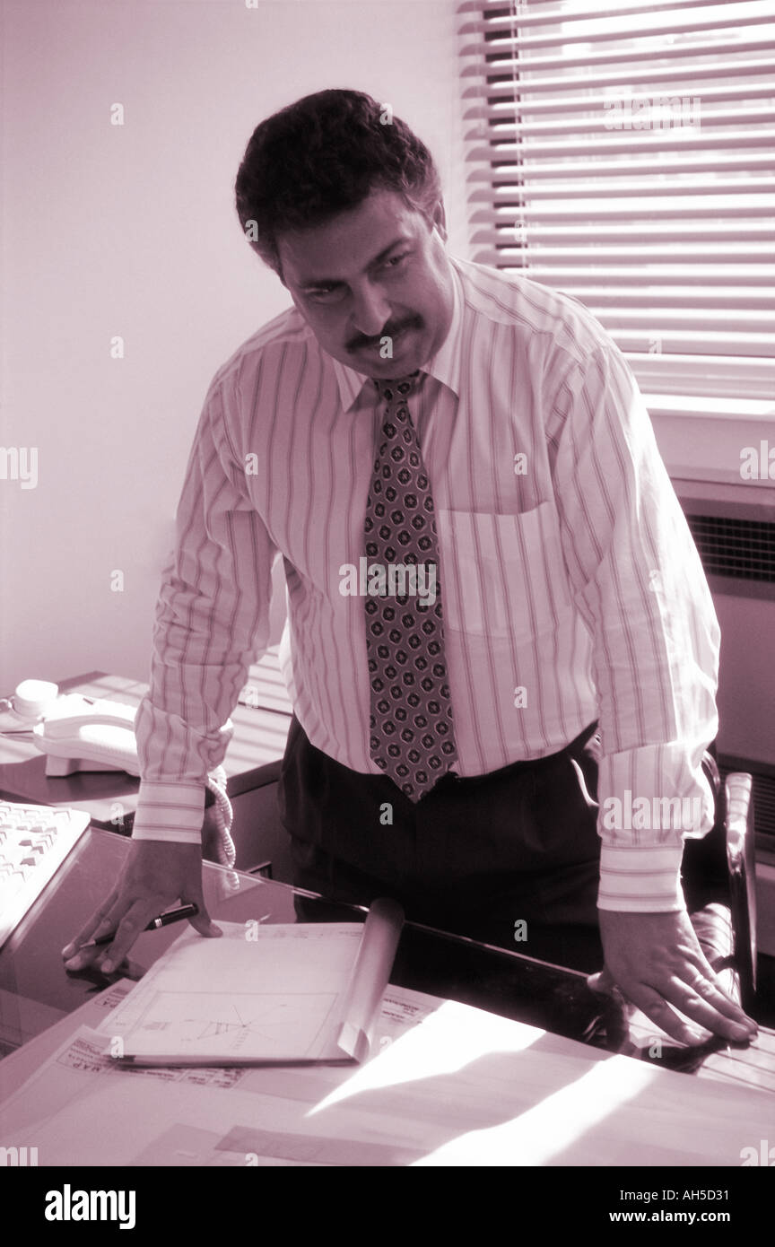 Office manager male standing alone at office desk Stock Photo - Alamy