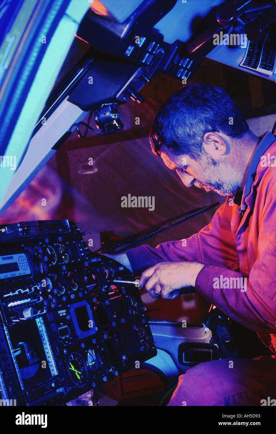 Aircraft engineer working on helicopter cockpit servicing controls ...