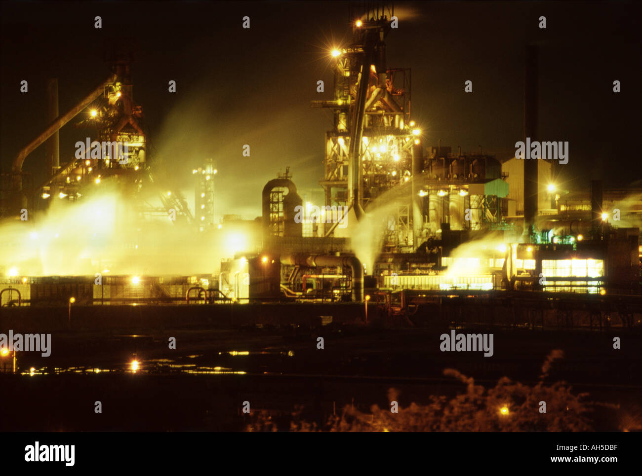 Portalbot steelworks in South Wales at night with steam and bright ...