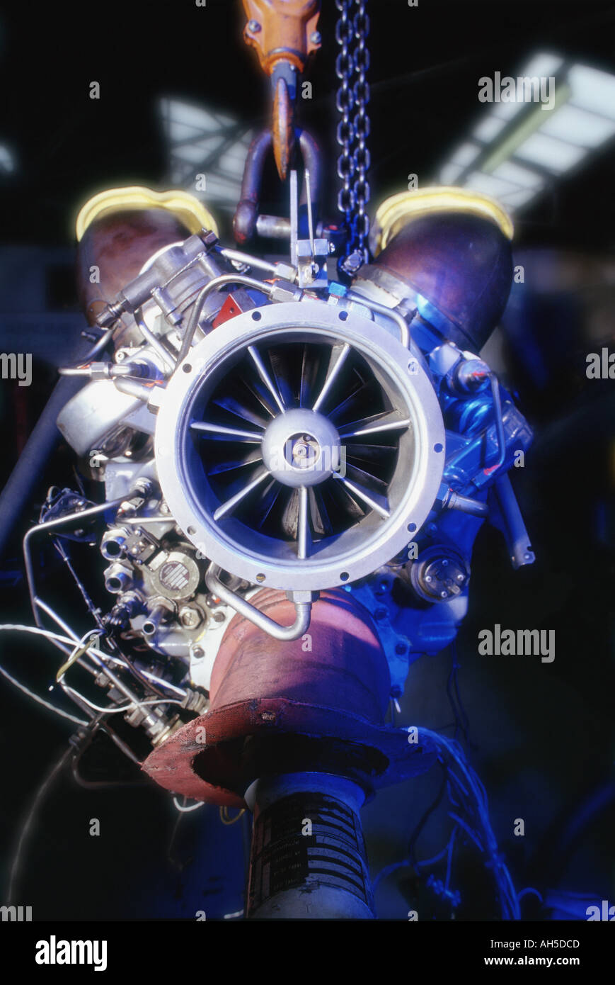 Helicopter turbine engine suspended on crane hook in aircraft hanger ...