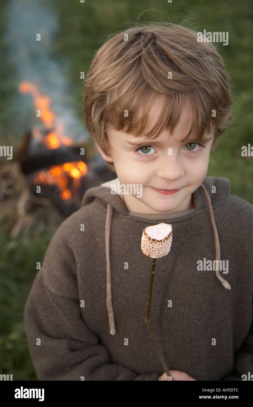 boy looking cheeky toasting marshmallows in garden outside Stock Photo ...