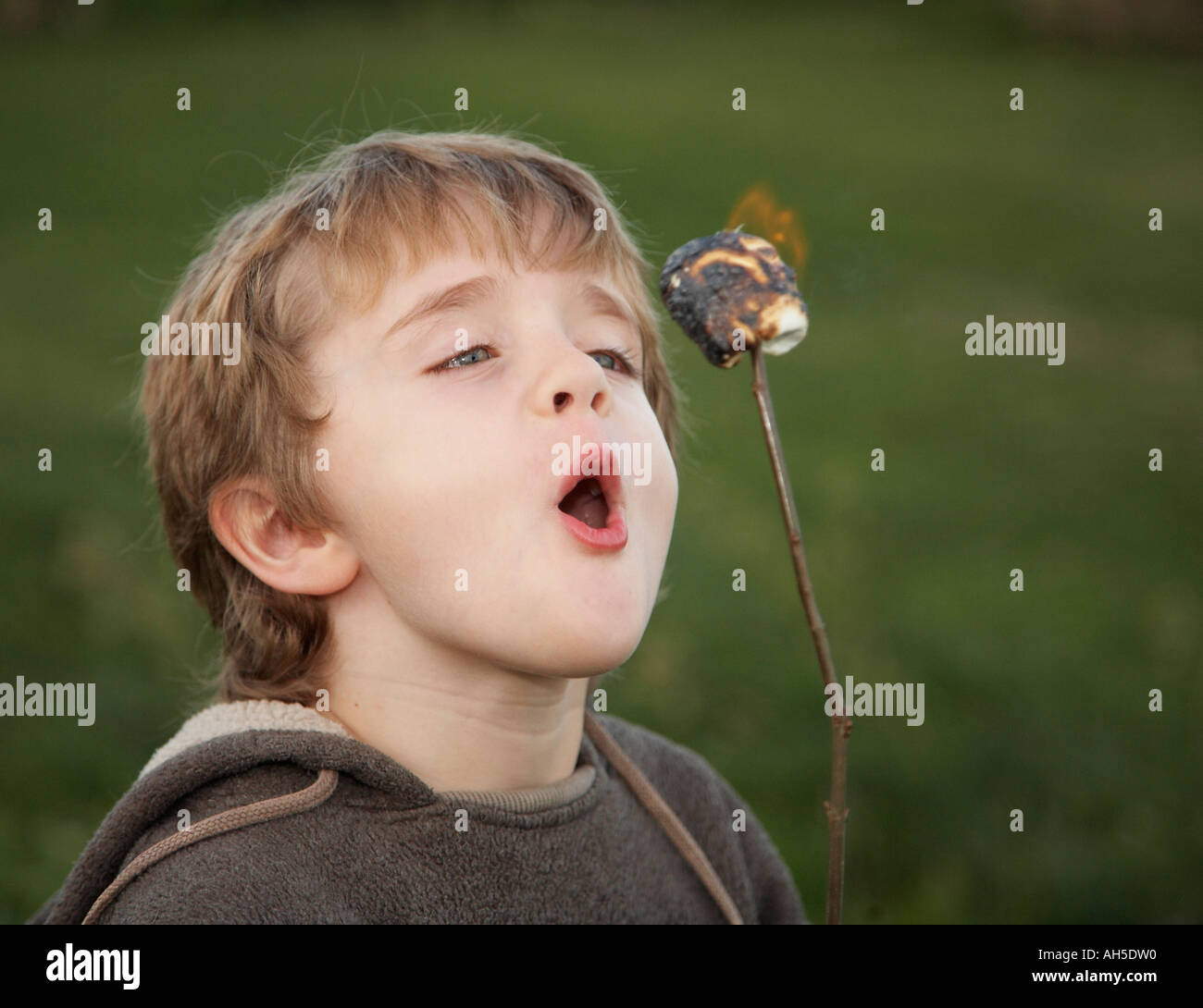 boy blowing flames of marshmallow outside Stock Photo - Alamy