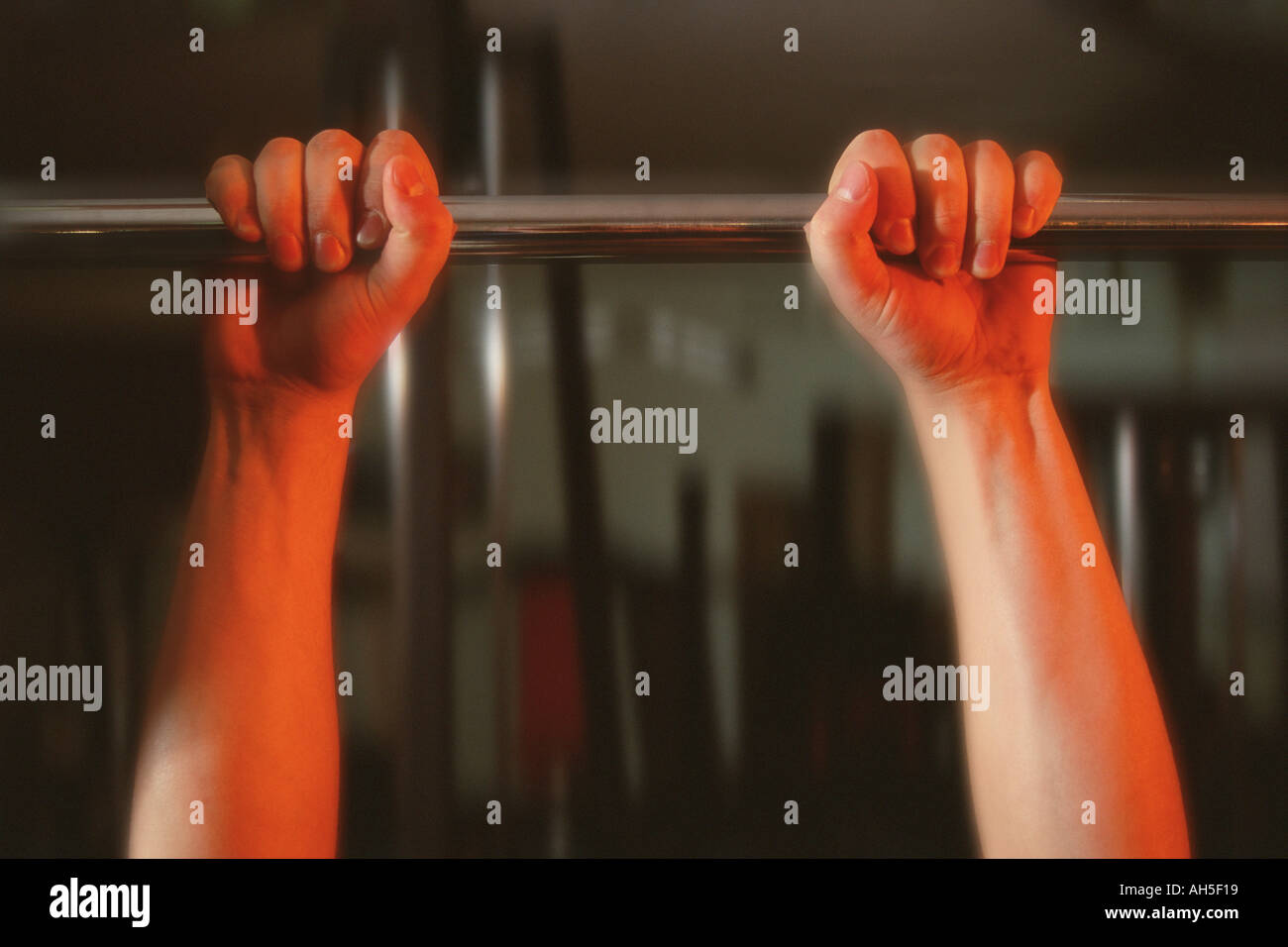 Male doing bar exercises in gym with warm light on arms Stock Photo - Alamy