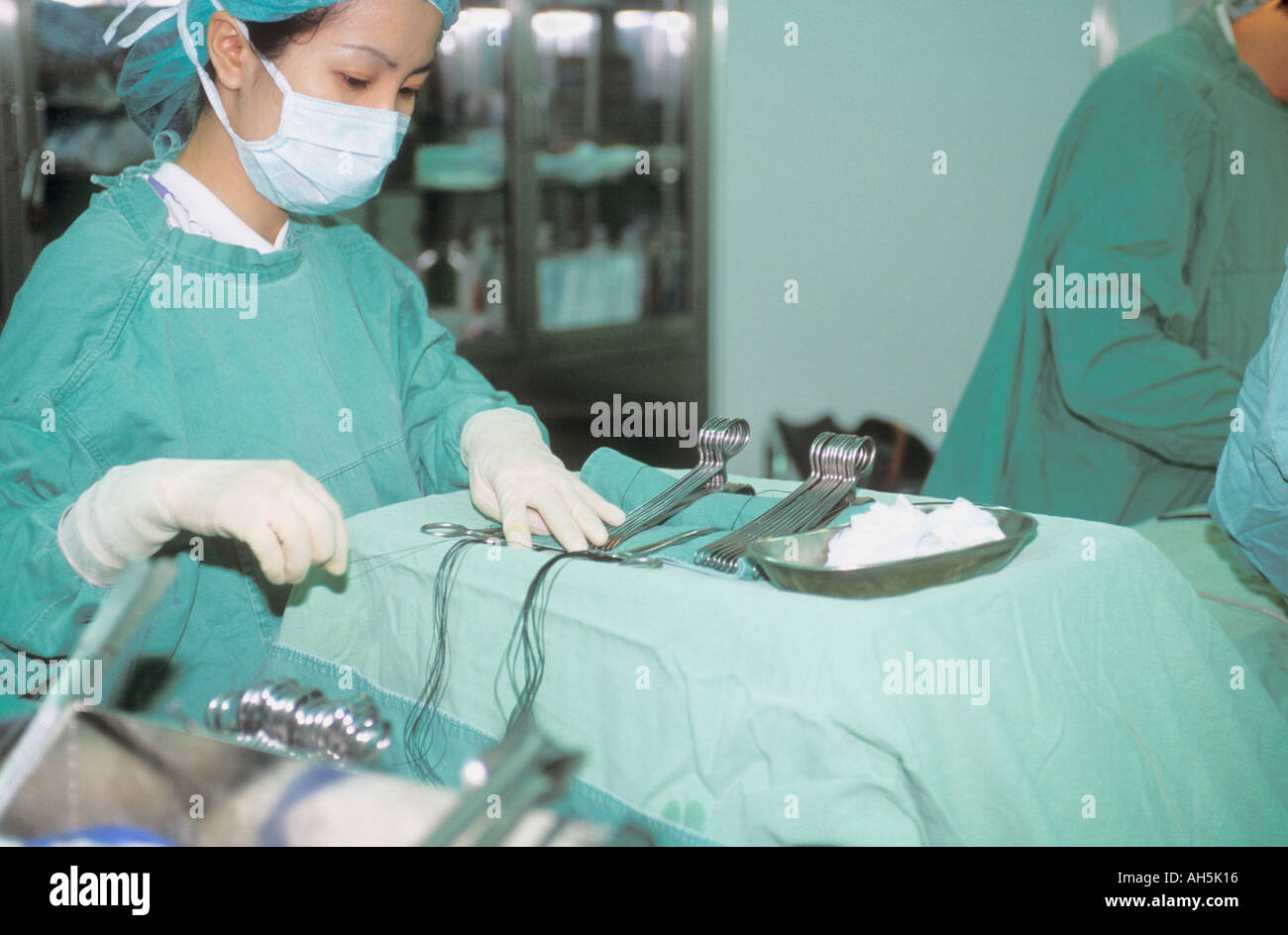 Nurse lining up clamps during surgery in hospital operating room OR ...