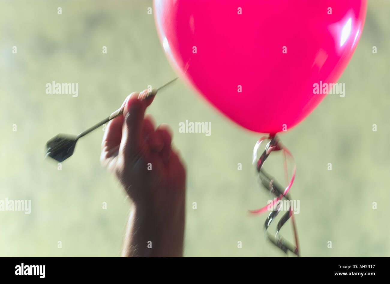Hand Popping Party Balloon with Dart Stock Photo - Alamy