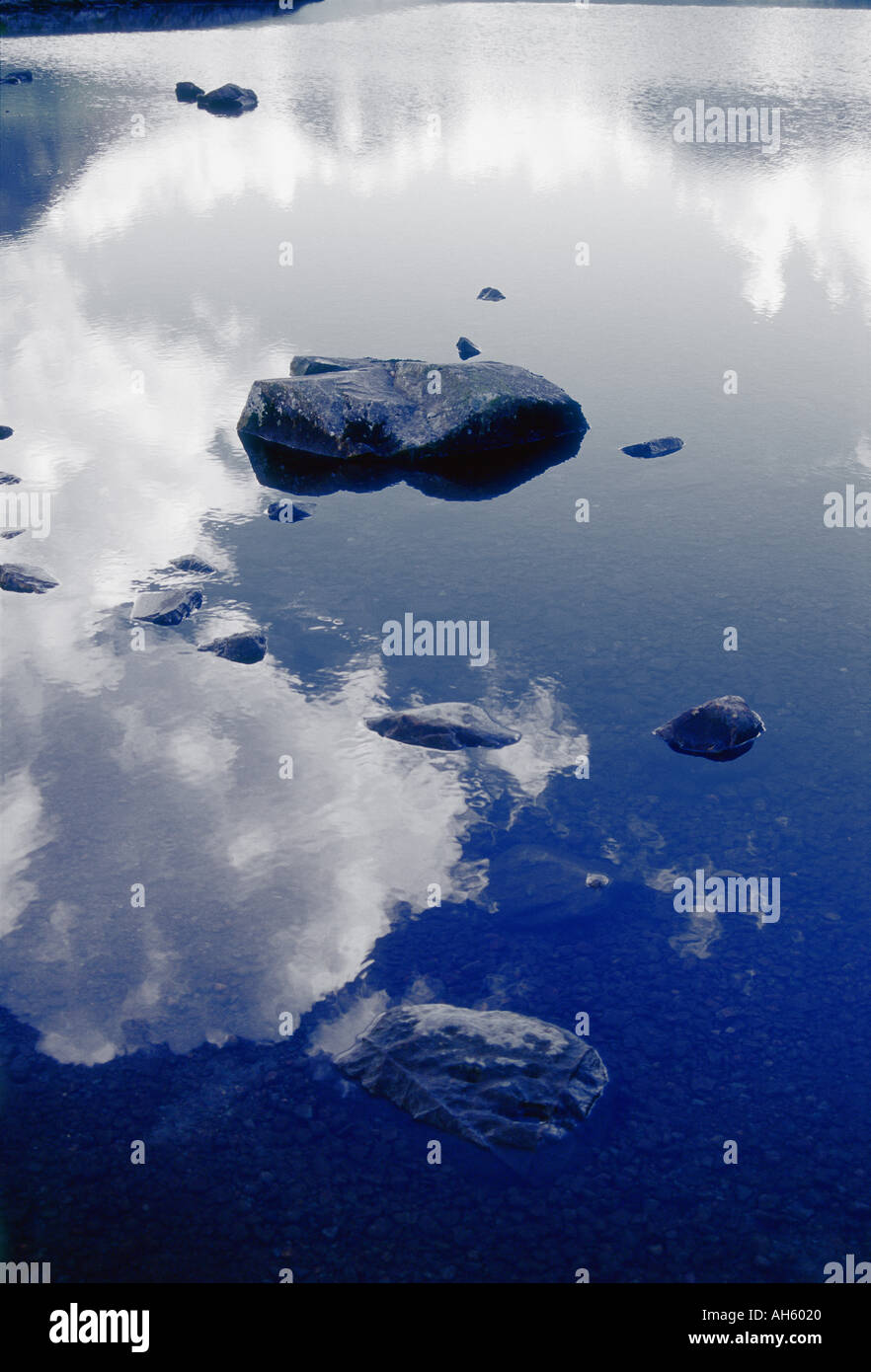 Rocks in water with reflection of sky and clouds Stock Photo - Alamy