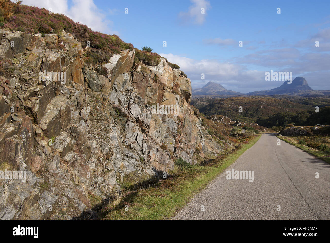 Gneiss rockface beside road with view of mountains Stock Photo - Alamy