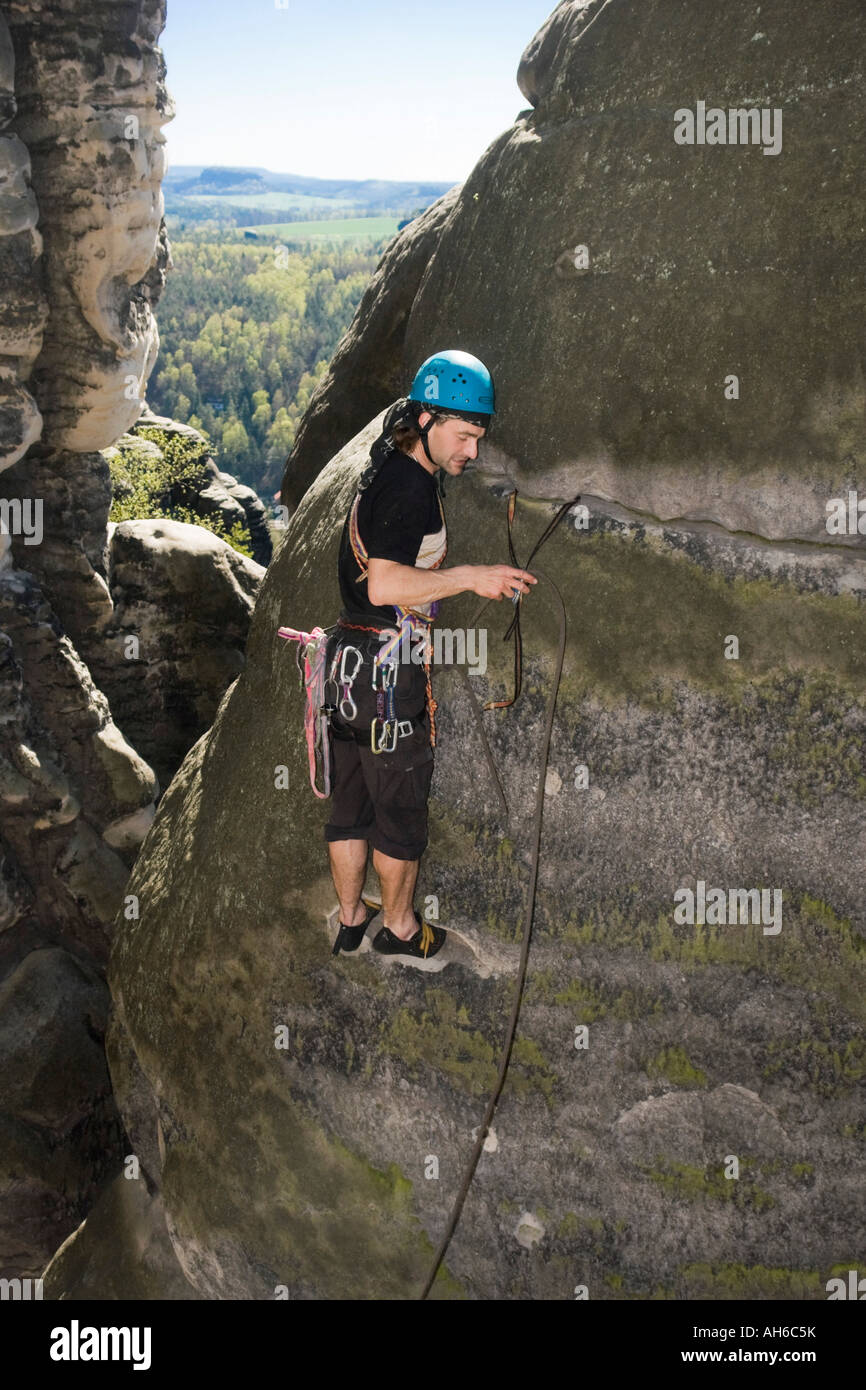 Climber clipping rope through a sling that is threaded through a hole ...