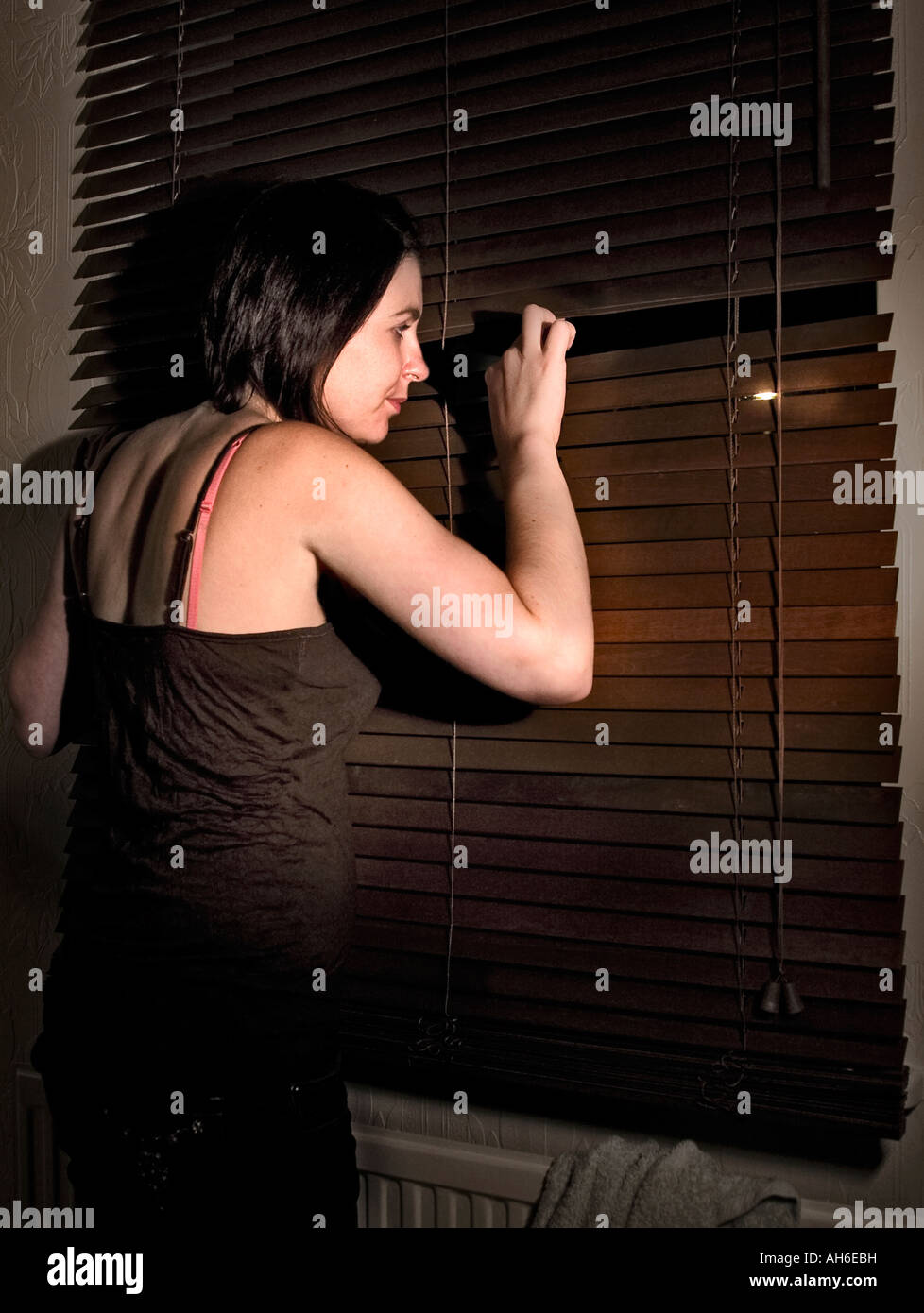 Woman Peering through window blinds at night Stock Photo - Alamy
