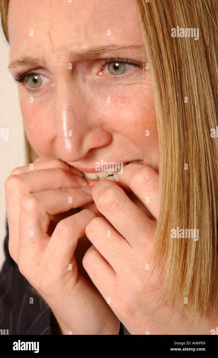 Young woman biting her nails in worry and anxiety Stock Photo - Alamy