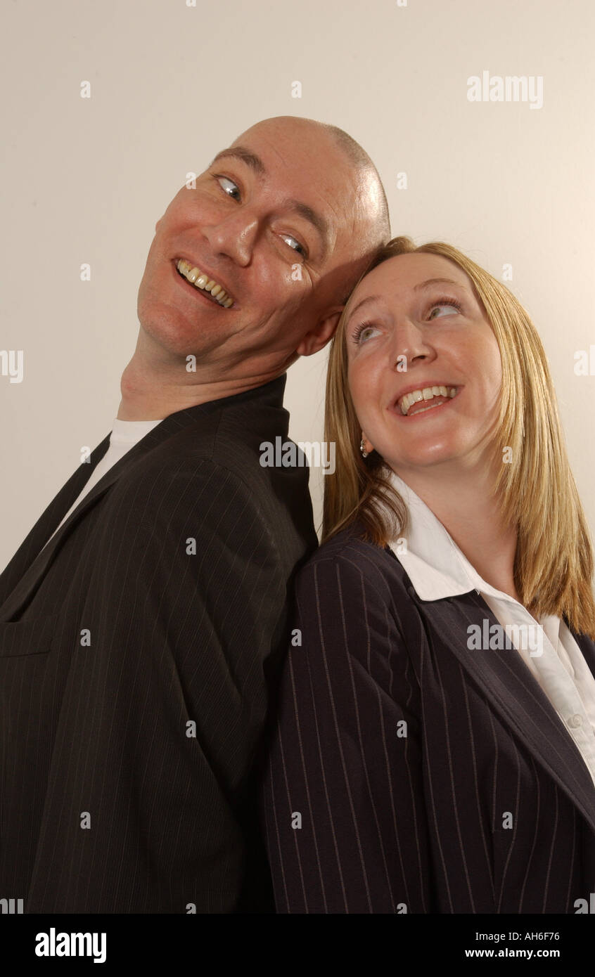 Young couple leaning back to back measuring their height and laughing ...