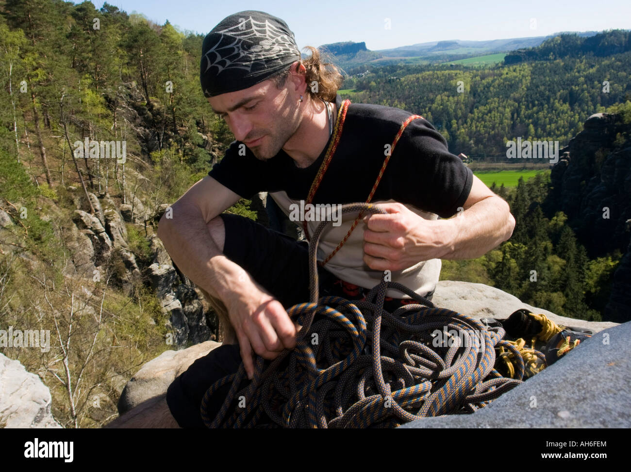 Free climber coiling rope on top of rock Hirschgrund Elbe Sandstone ...