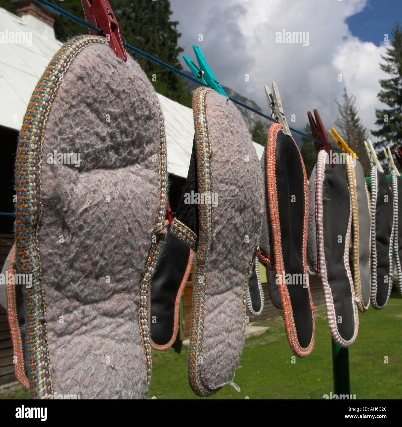 close up of a row of house slippers drying in the sun on a laundry line ...