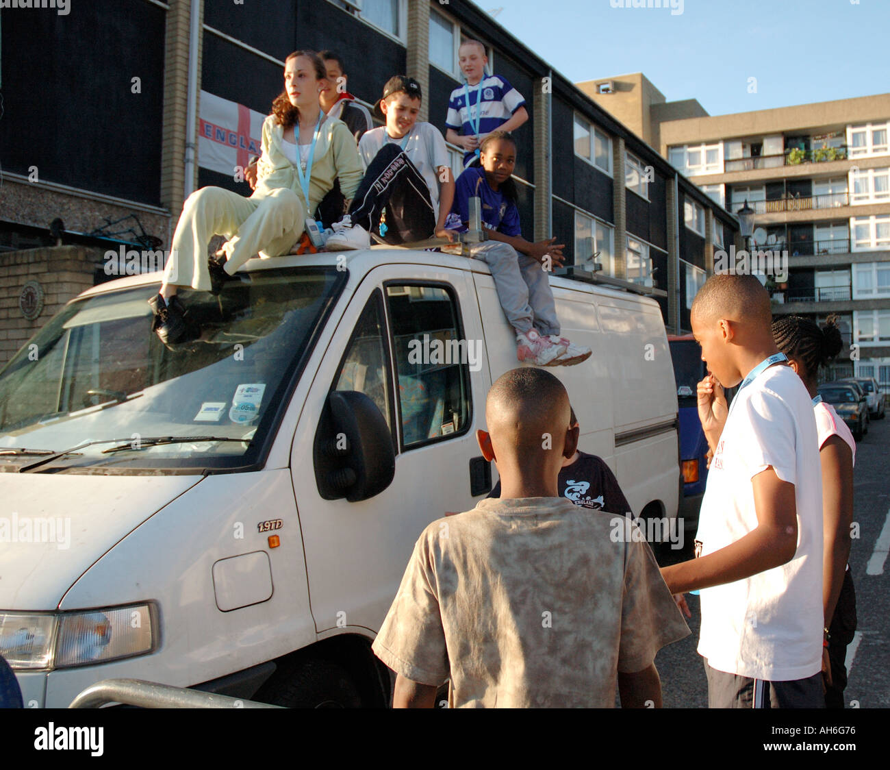 Lively group of children climbing and jumping on van parked on their ...