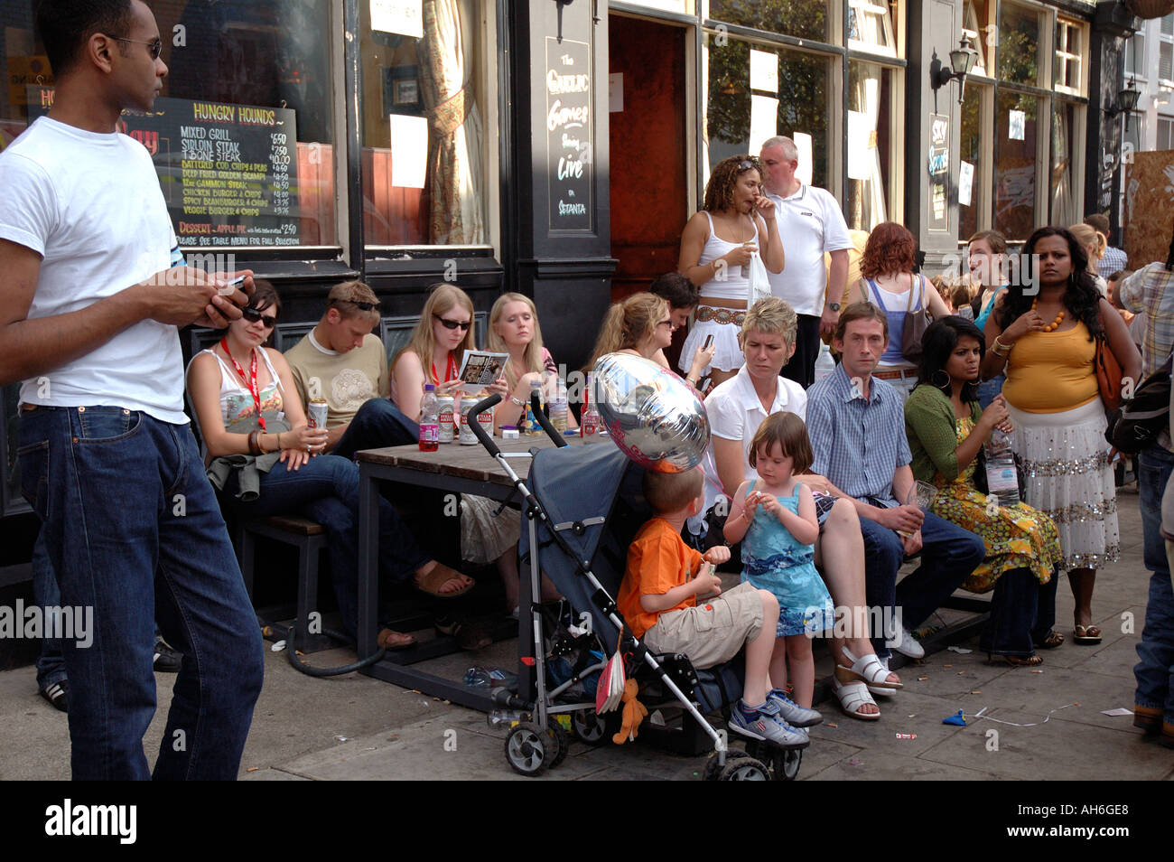 Multi-cultural group of people sitting outside pub drinking and ...