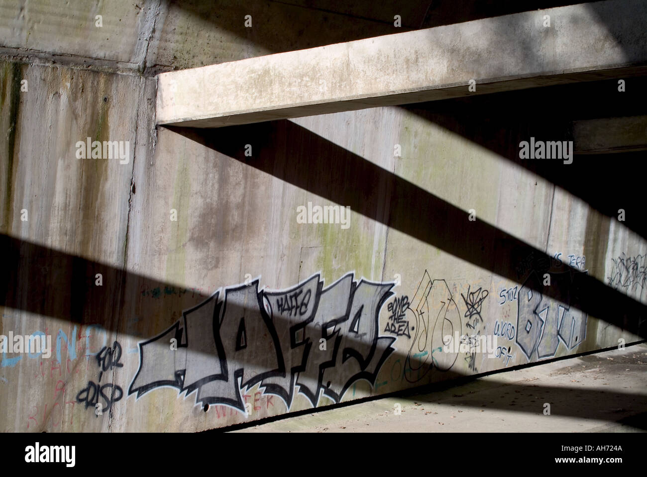Graffiti on a concrete wall with sunlight casting a diagonal shadow ...