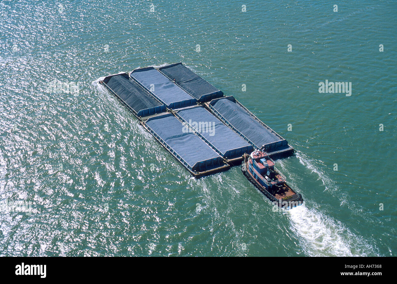 Tug boat pushing barges loaded with crushed rock in New York harbor ...