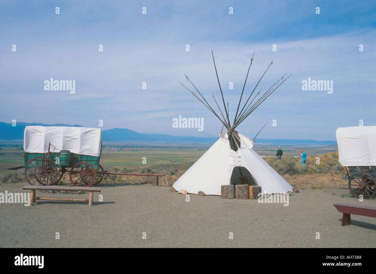 A covered wagon and teepee stand outside of the Oregon Trail Museum in ...