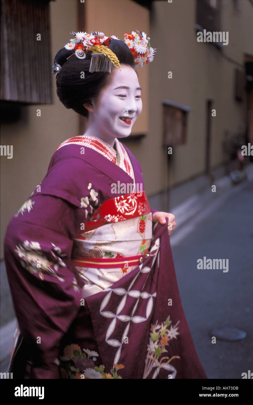 A maiko in full kimono and makeup heading out to an evening appointment ...