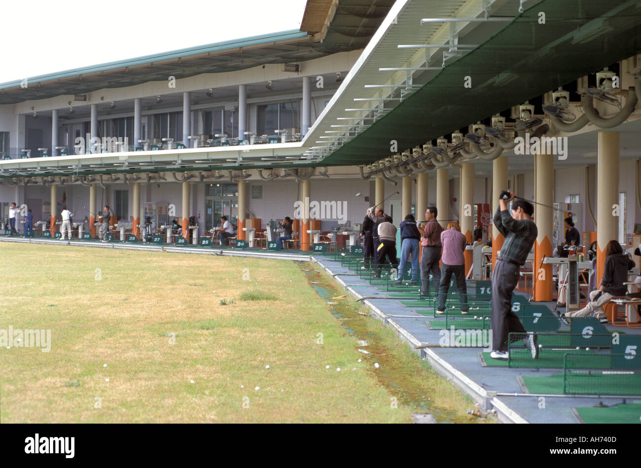 Golfers practicing their swing at a two-tier golf practice driving ...