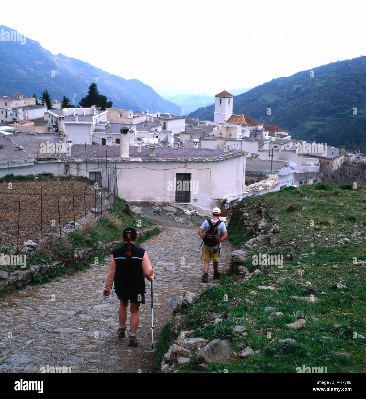Two people walking above the village of Capileira in the Alpujarras ...