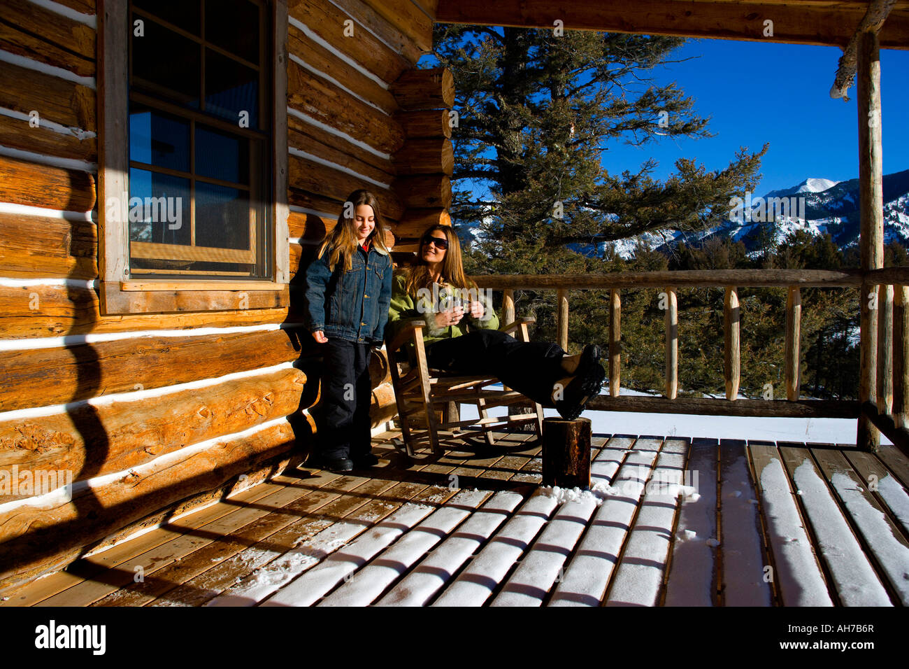 Mid adult woman sitting in a rocking chair with her daughter standing ...