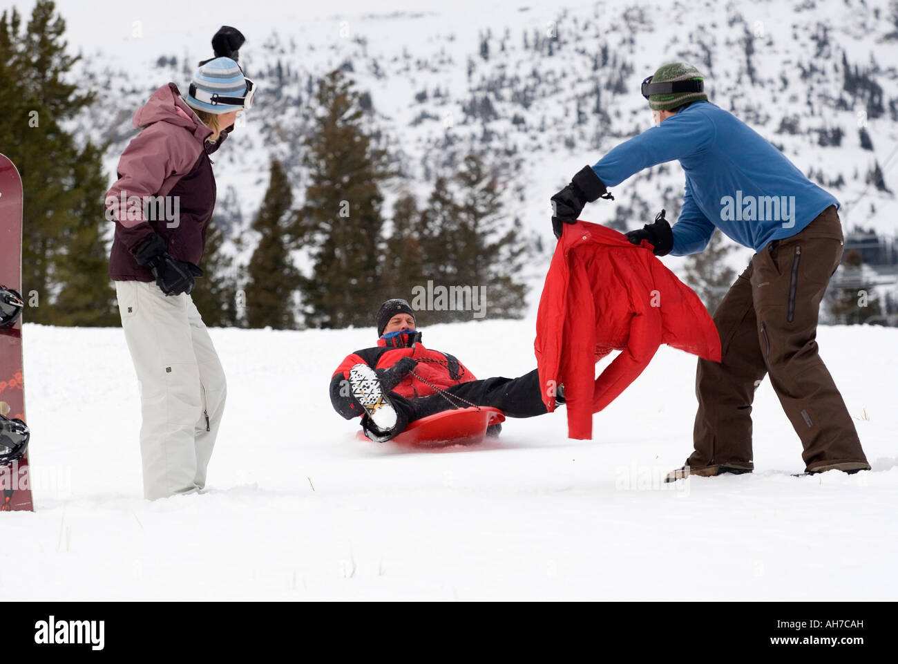 Mid adult man sledding between a mid adult man and a mid adult woman ...