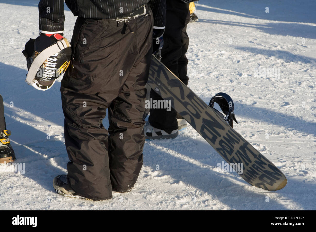 Low section view of two people standing with a snowboard Stock Photo ...
