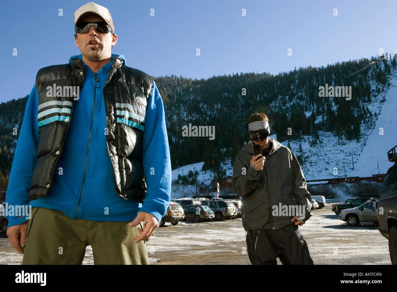 Mid adult man standing with a young man operating a mobile phone behind ...