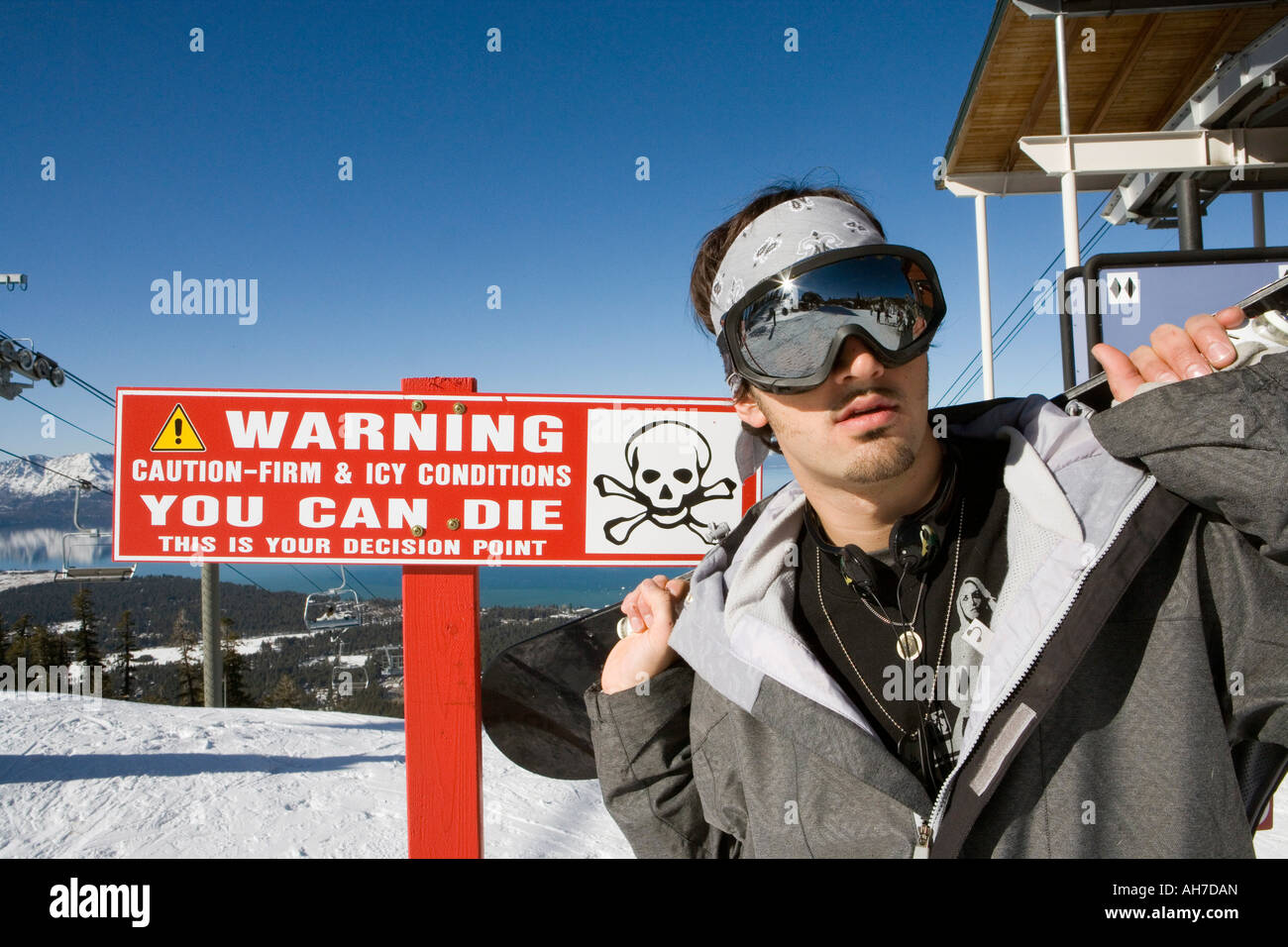 Young man carrying a snowboard in front of a warning sign Stock Photo ...