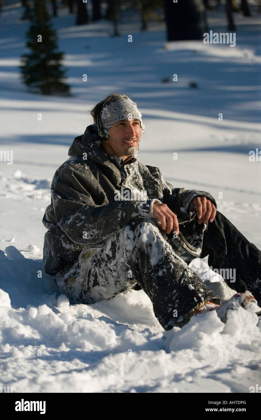 Young man sitting on snow Stock Photo - Alamy