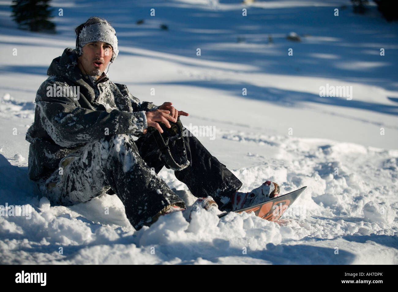Young man sitting on snow Stock Photo - Alamy