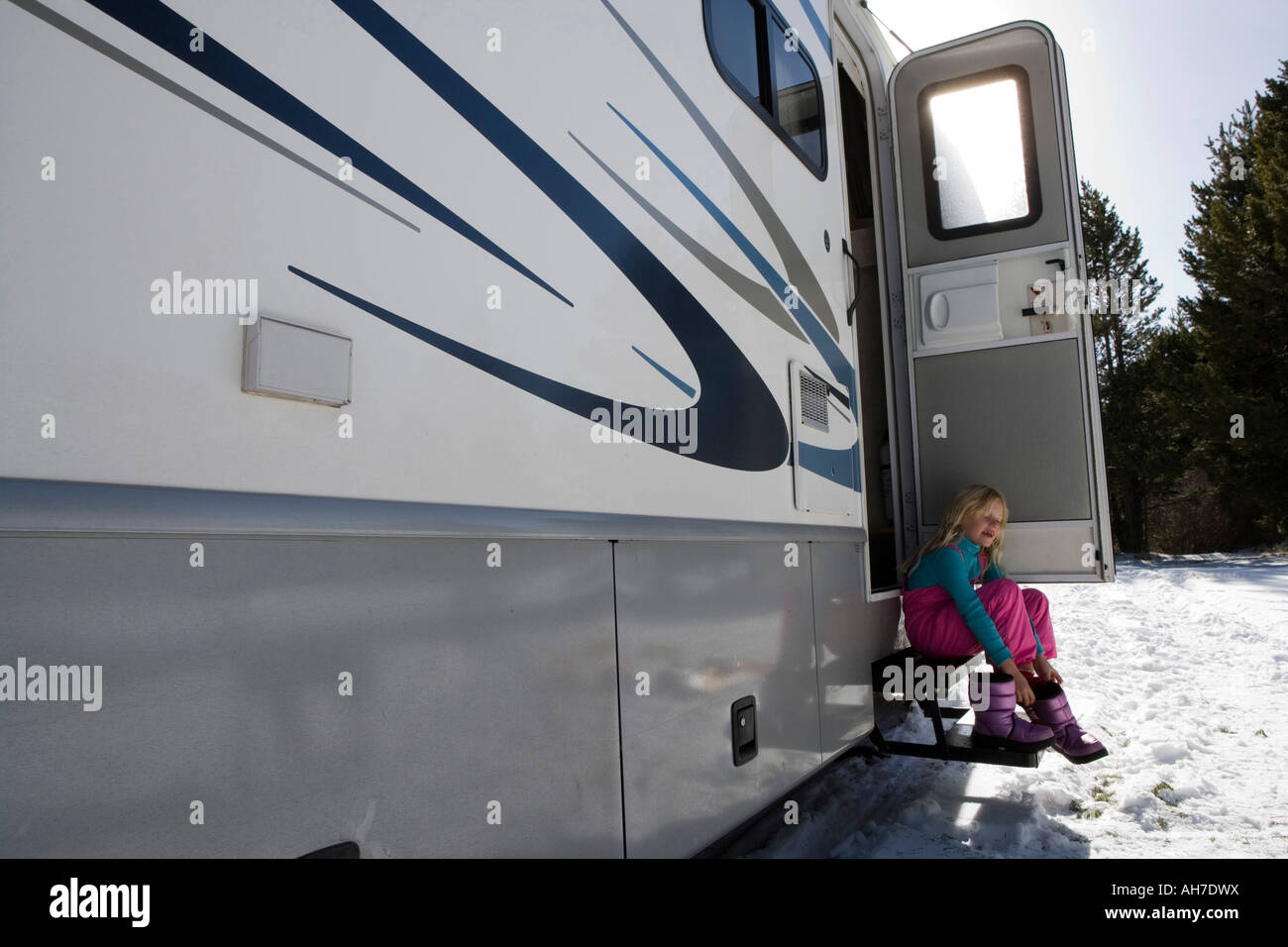 Girl sitting on the steps of a recreational vehicle and putting on her ...