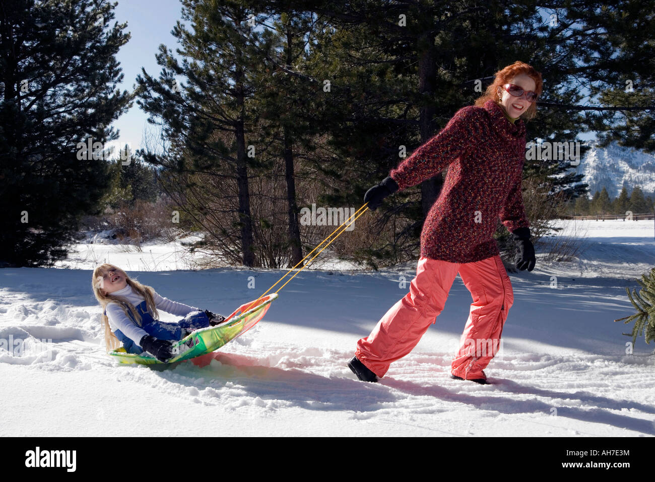 Mature woman pulling her daughter on a sled Stock Photo - Alamy
