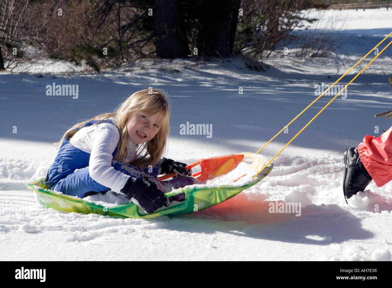 Girl being pulled on a sled Stock Photo - Alamy